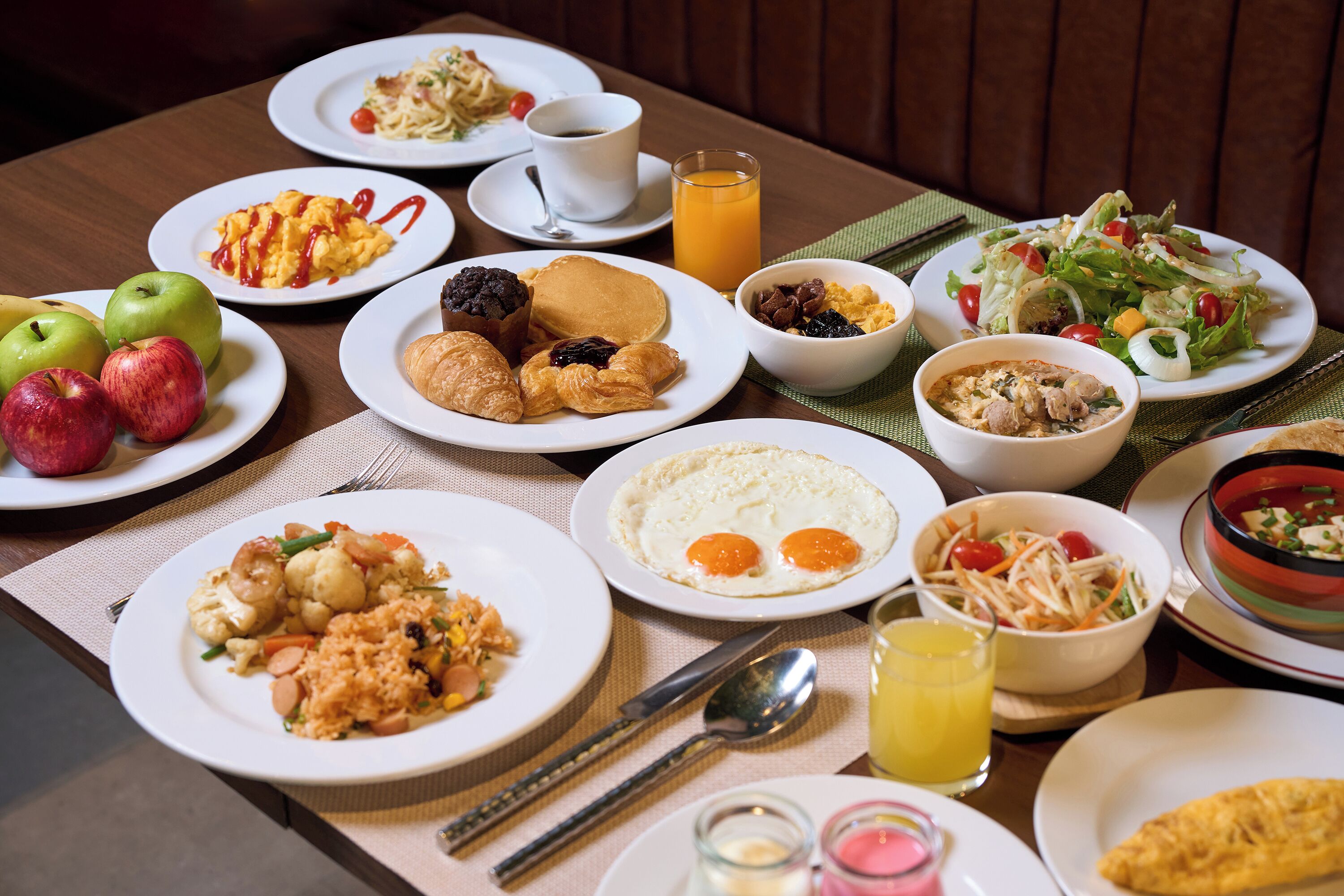 Um buffet de café da manhã com diversos pratos, incluindo ovos, panquecas e frutas.