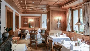 Uma sala de jantar com painéis de madeira, toalhas de mesa brancas e cadeiras estampadas.