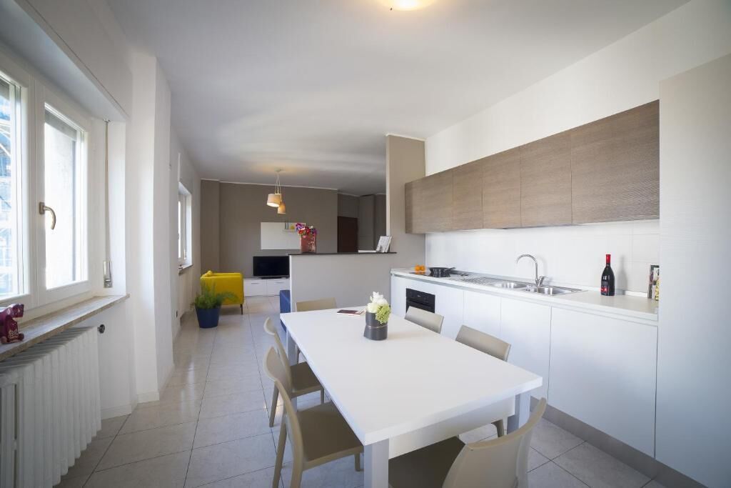 Cozinha moderna com armários brancos, mesa de jantar e forno embutido.