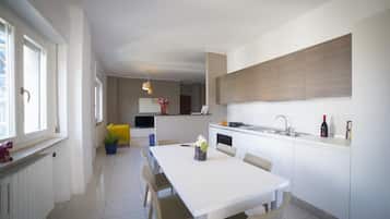 Cozinha moderna com armários brancos, mesa de jantar e forno embutido.