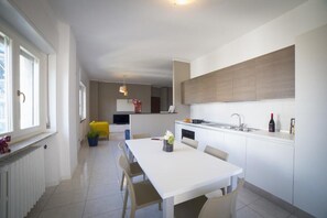 Cozinha moderna com armários brancos, mesa de jantar e forno embutido.
