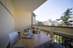Uma varanda com mesa, cadeiras e vista para a paisagem urbana.