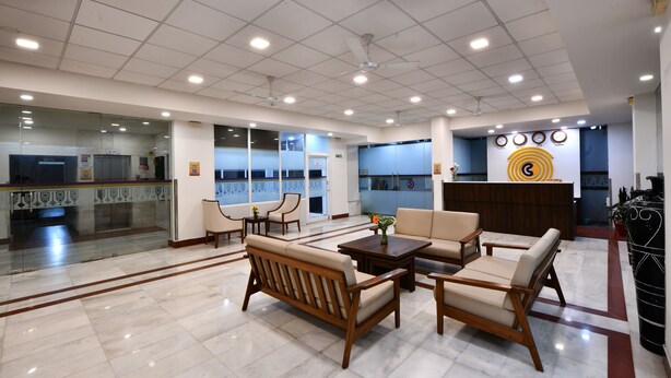 Um hall amplo com balcão de recepção, área de estar e uma grande janela.