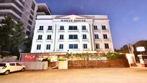 Um edifício com várias andares e varandas, identificado como "WHITE HOUSE BOUTIQUE RESIDENCES".