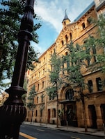 Um edifício histórico com uma entrada imponente, várias janelas e uma estátua no topo.