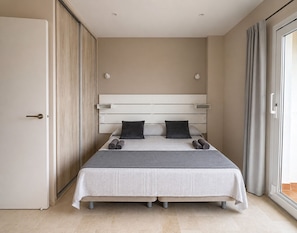 Um quarto moderno com uma cama grande, um guarda-roupa de madeira e uma porta de correr de vidro.