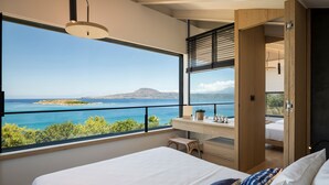 Quarto com uma grande janela que oferece vista para o mar e uma ilha distante.