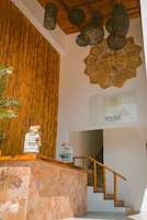 Uma escadaria com parede de pedra, guarda-corpo de bambu e luminárias decorativas penduradas.