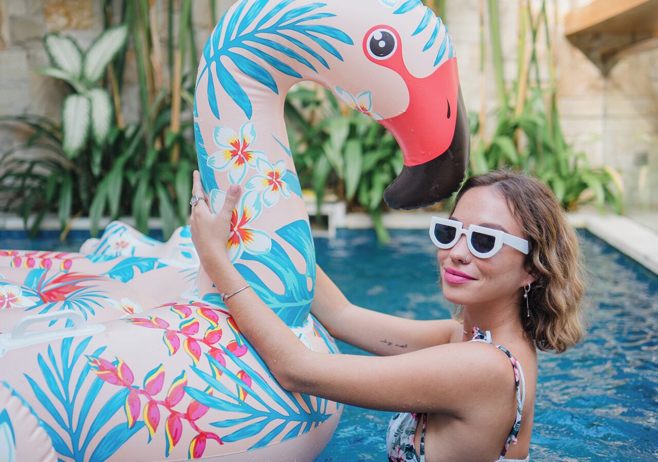 Uma pessoa em uma piscina com um boi de piscina em formato de flamingo.