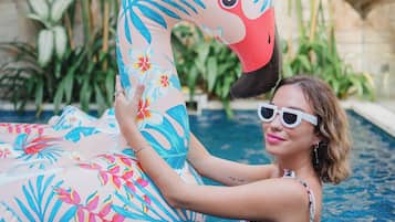 Uma pessoa em uma piscina com um boi de piscina em formato de flamingo.