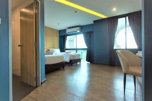 Quarto de hotel moderno com piso de madeira, duas camas, uma escrivaninha e uma cadeira.