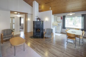 Uma sala de estar ampla com lareira, piso de madeira e uma mesa de jantar com cadeiras.