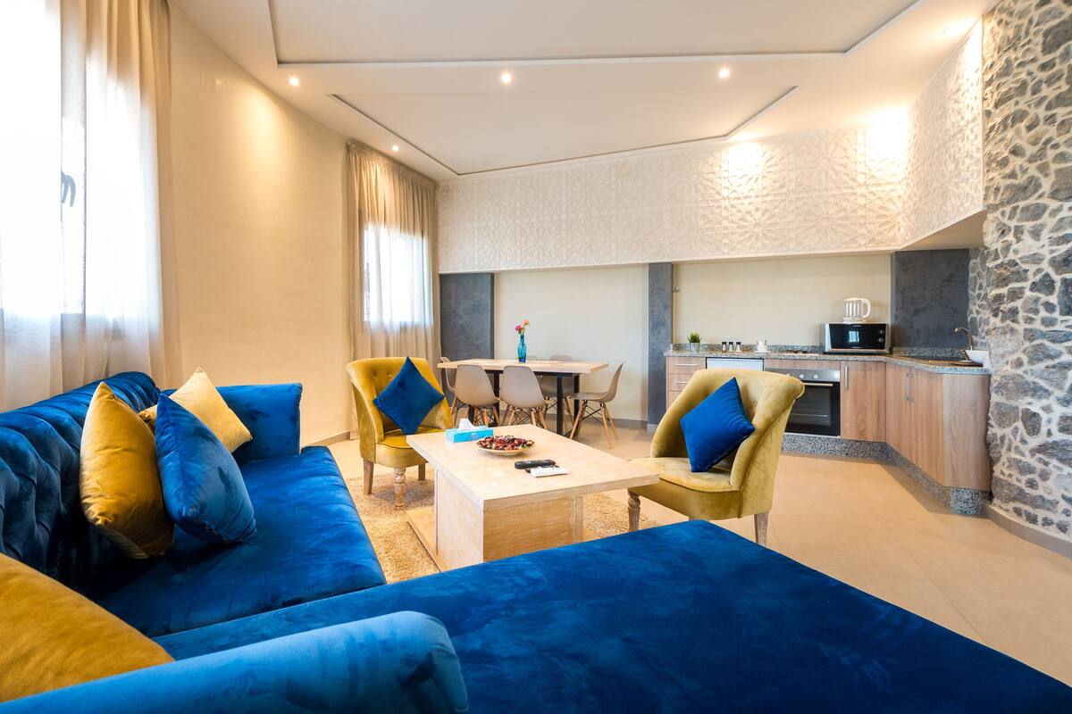Uma sala de estar moderna com um sofá azul, uma mesa de centro e cadeiras amarelas.