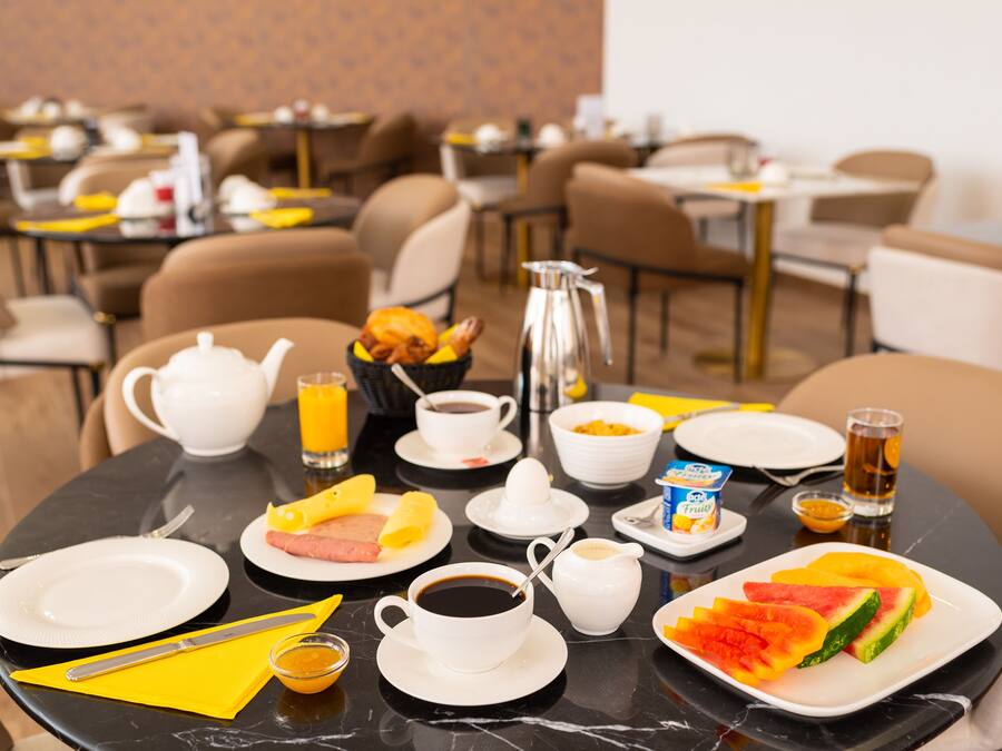 Uma mesa de café da manhã posta com pratos, xícaras e uma jarra de café.