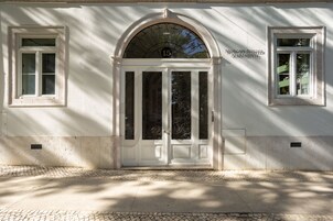 Fachada de um edifício com uma grande entrada em arco, número 15, e duas janelas de cada lado.