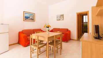 Um espaço compacto com mesa de jantar, cadeiras, sofá e televisão.