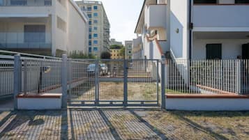 Área residencial murada com edifícios modernos, céu claro e terreno pavimentado.