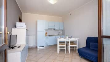Um espaço de estar compacto com cozinha compacta, área de refeições e sofá.