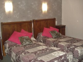 Uma cama de casal com roupa de cama estampada e duas luminárias na parede.