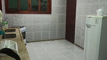 Uma cozinha compacta com bancada de granito, pia embutida, janela com moldura de madeira e geladeira branca.