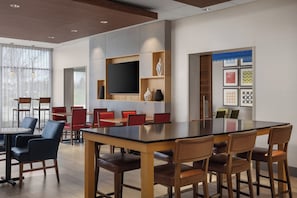 Uma sala de jantar moderna com uma mesa grande, cadeiras vermelhas e uma parede com lousa.