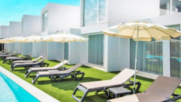 Um hotel moderno com área de piscina, espreguiçadeiras e guarda-sóis.
