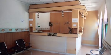 Uma área de recepção com balcão, cadeiras e um relógio fixado na parede.