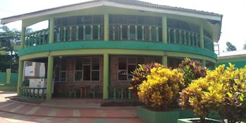 Um edifício de dois andares com fachada verde e uma varanda no andar superior.