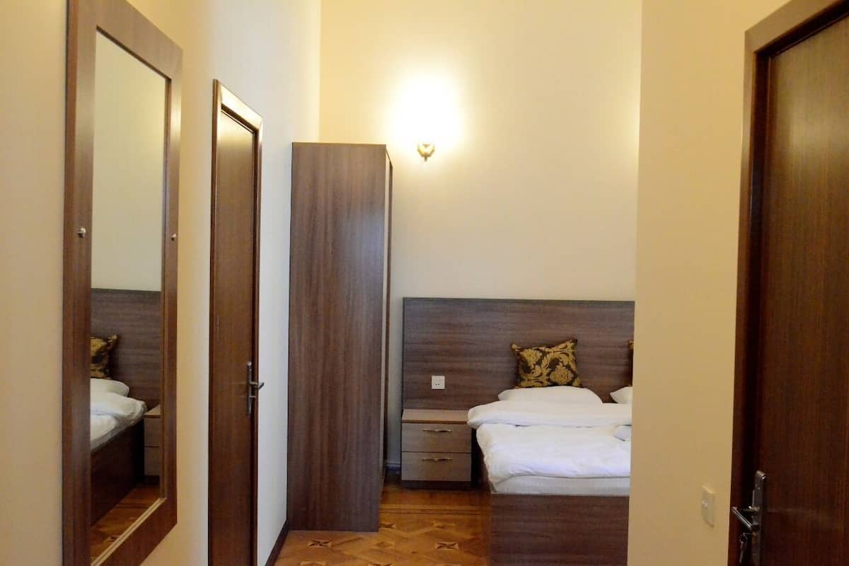 Quarto com cama, guarda-roupa, mesa de cabeceira e luminária fixada na parede.