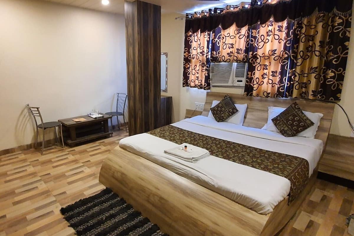 Quarto de hotel com uma cama grande, uma escrivaninha, uma cadeira e uma mesinha.