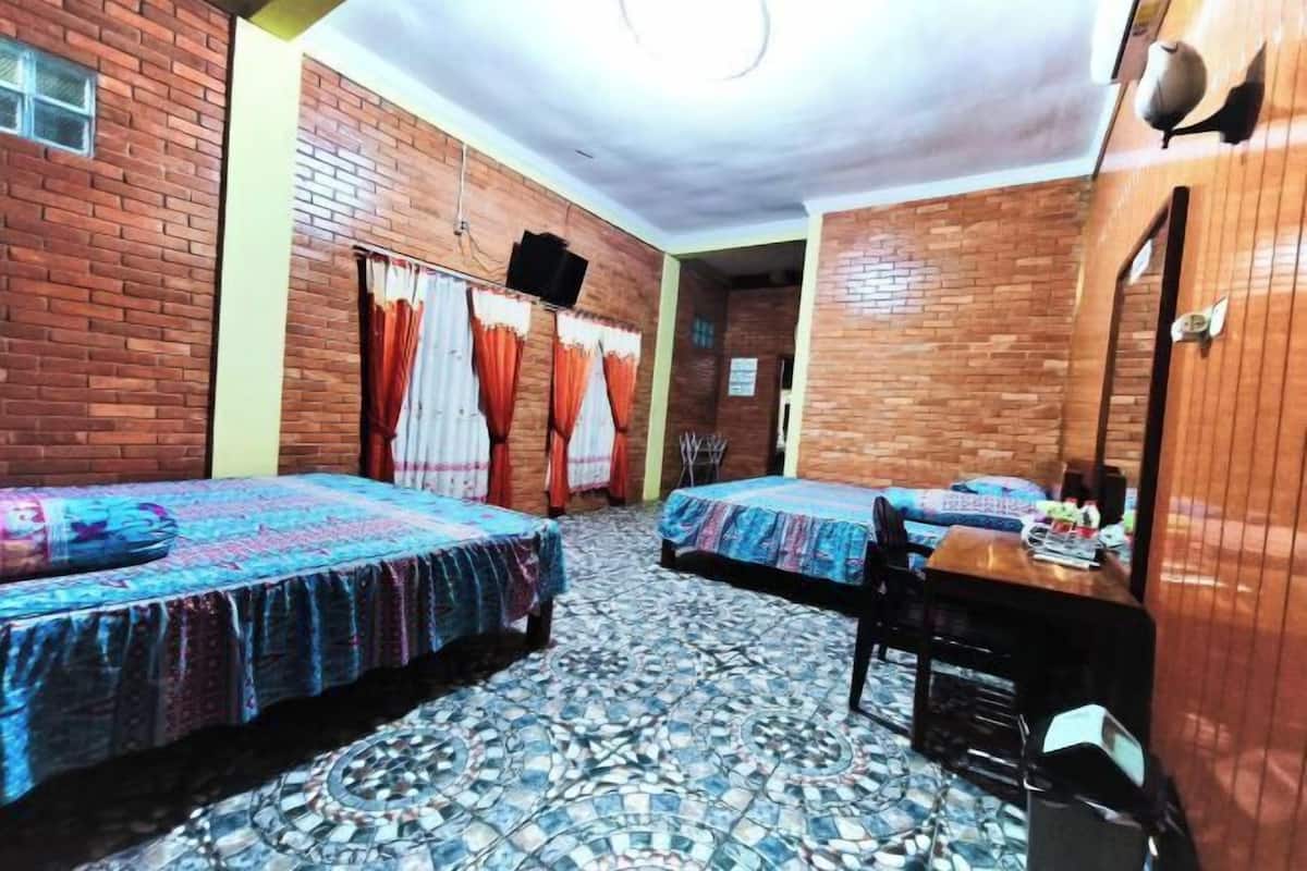 Quarto com duas camas, uma mesinha e uma cadeira.