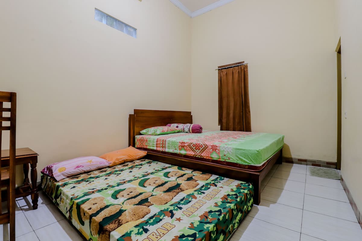 Quarto com duas camas, uma cadeira de madeira e uma janela pequena.