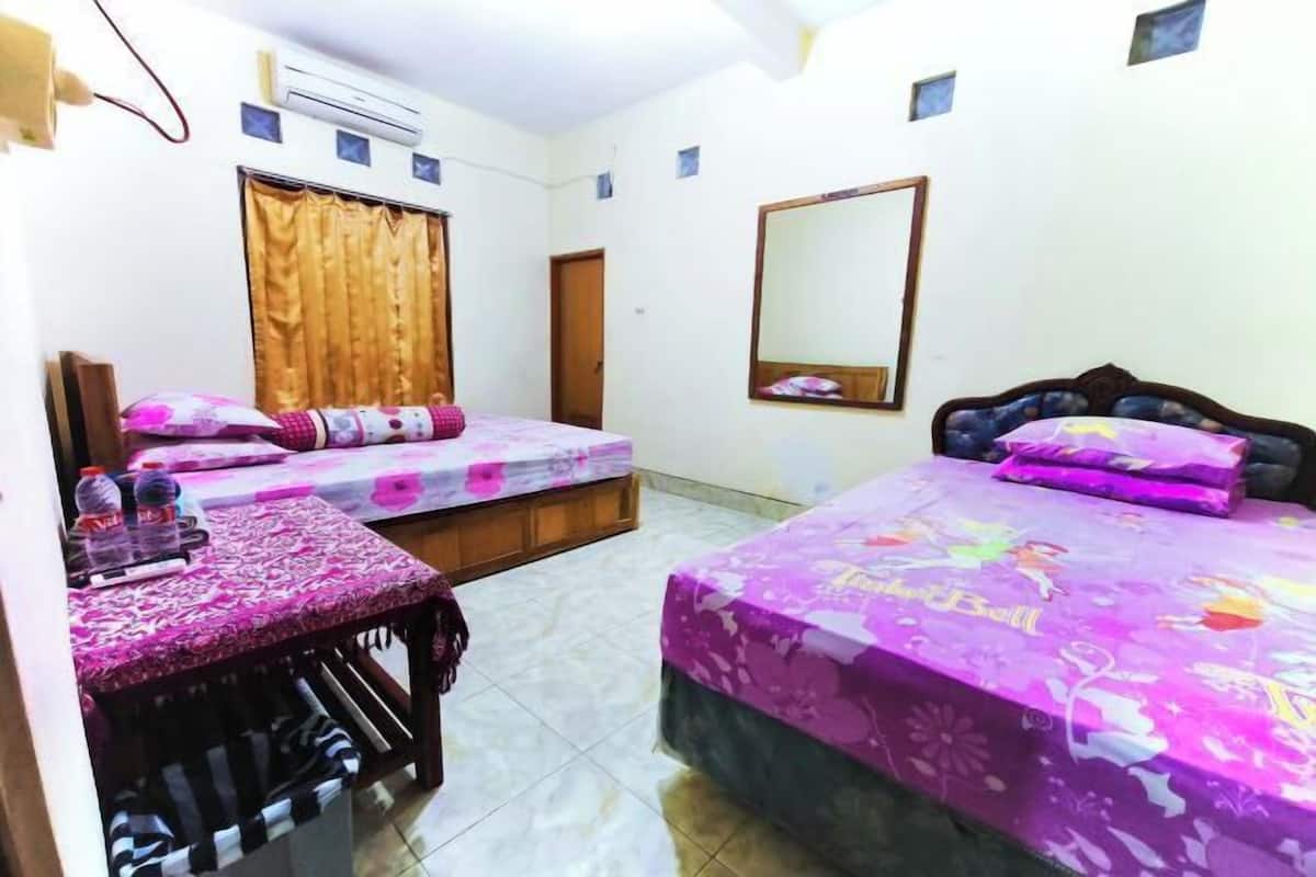 Quarto com duas camas, uma mesa, um espelho e uma porta.