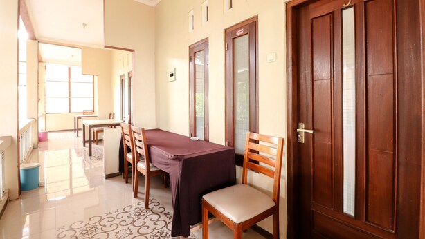 Quarto com porta de madeira marcada com o número 9, uma mesa de jantar com cadeiras e um chão estampado.
