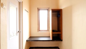 Um quarto com porta, janela e prateleira embutida.