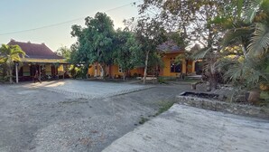 Um pátio com área pavimentada, rodeado por edifícios com telhados em cerâmica e vegetação.