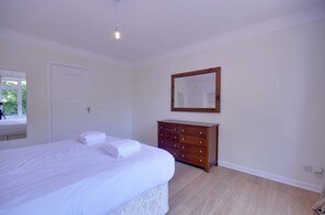 Um quarto com uma cama, cômoda, espelho e janela.