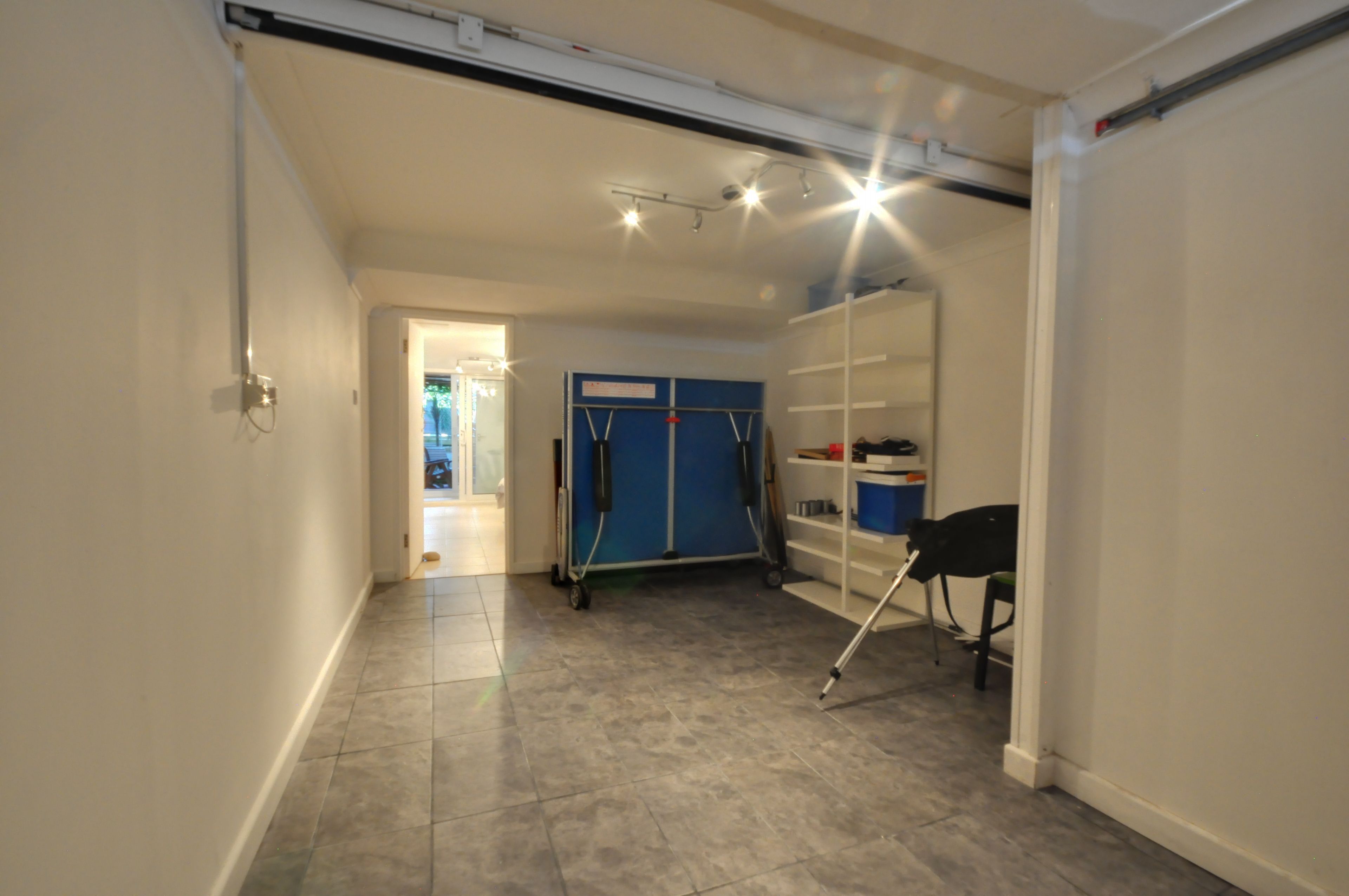Corredor com porta deslizante, equipamento de exercício azul e uma cadeira.