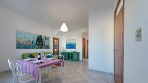 Uma área de refeições com uma mesa posta para dois, um armário verde e duas pinturas na parede.