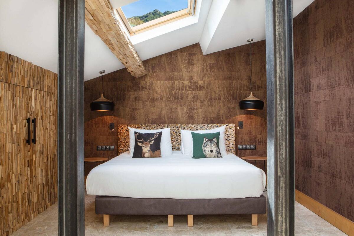 Quarto moderno com uma cama grande, paredes de madeira e um claraboia.