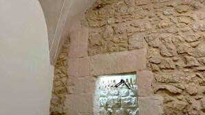 Quarto com parede de pedra e claraboia.