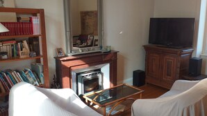 Uma sala de estar com lareira, televisão e estante de livros.