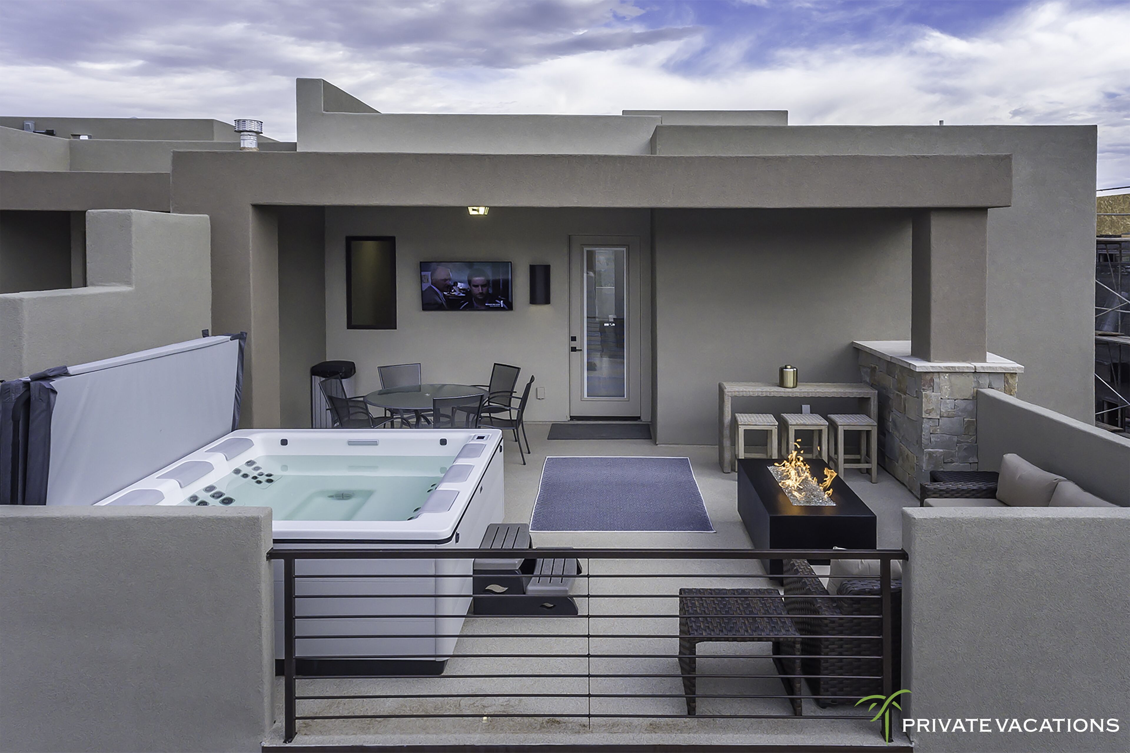 Um terraço no terraço com hidromassagem, área de estar e lareira.