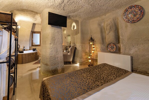 Quarto com cama, um banco de madeira, um espelho, televisão e parede com padrão.