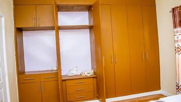 Quarto com guarda-roupa, cama e mesa de cabeceira.