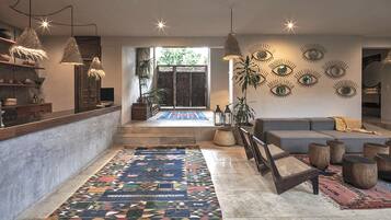 Uma sala de estar ampla com sofá, tapete estampado e parede com detalhes decorativos em formato de olhos.