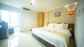 Quarto de hotel com cama, escrivaninha, guarda-roupa e janela.