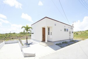 Um edifício térreo com telhado plano e uma pequena varanda.