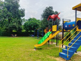 Um parquinho com escorregador, estruturas de escalada e uma parede de escalada vermelha.