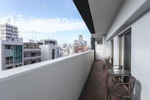 Uma varanda com vista para a cidade, uma mesa e duas cadeiras.